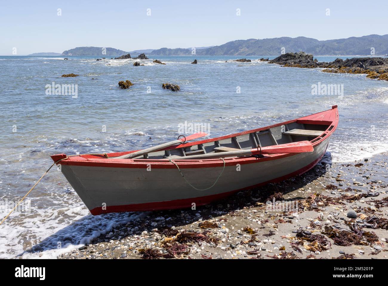 Red and white painted rowing boat at the beach at Isla Maiquillahue in ...