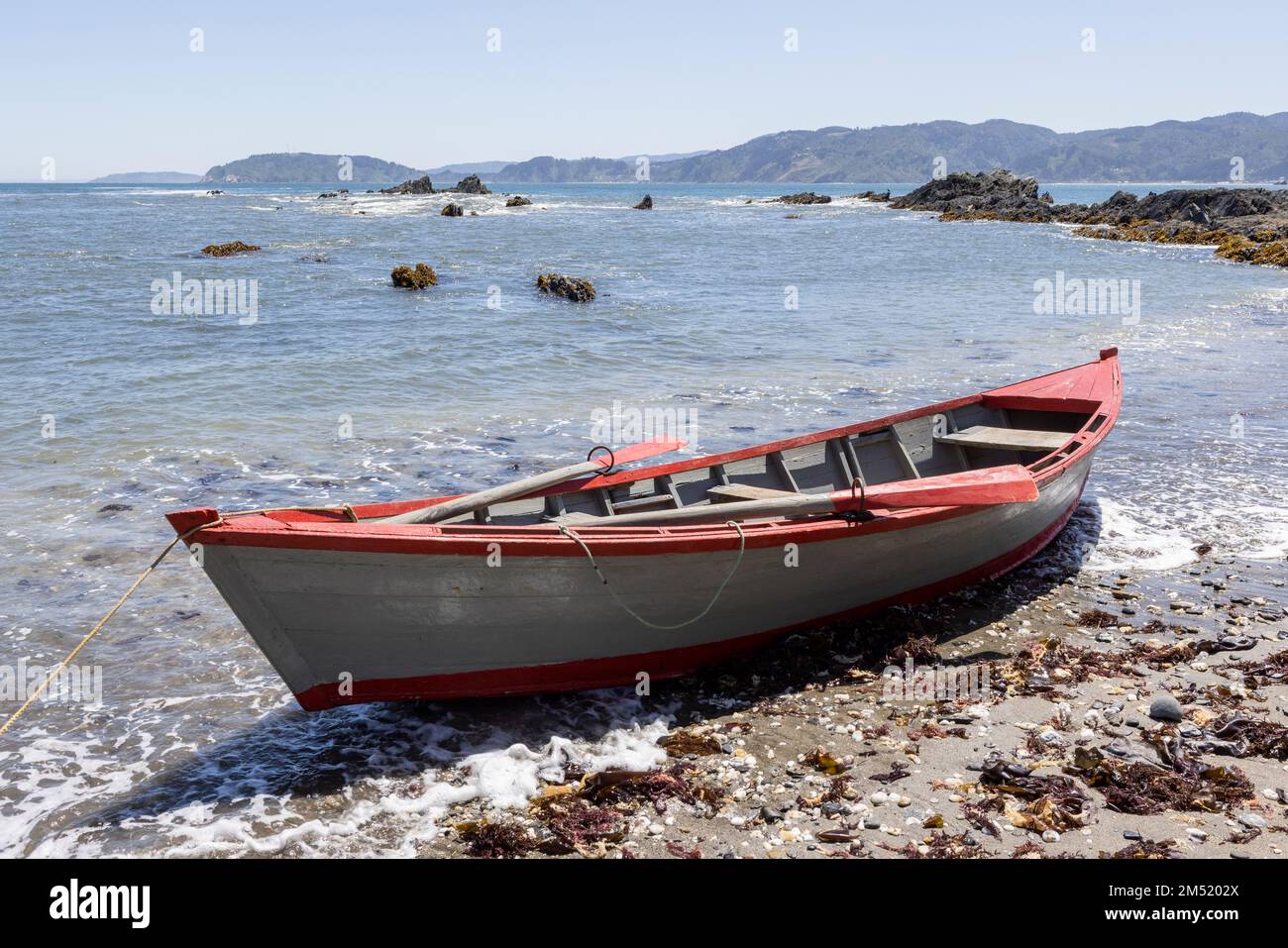 Red and white painted rowing boat at the beach at Isla Maiquillahue in ...