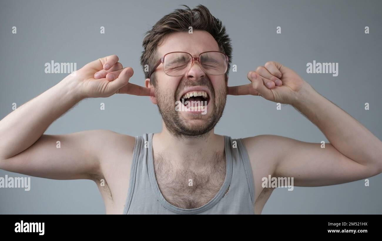 Unhappy stressed out caucasian man plugging ears with fingers ...
