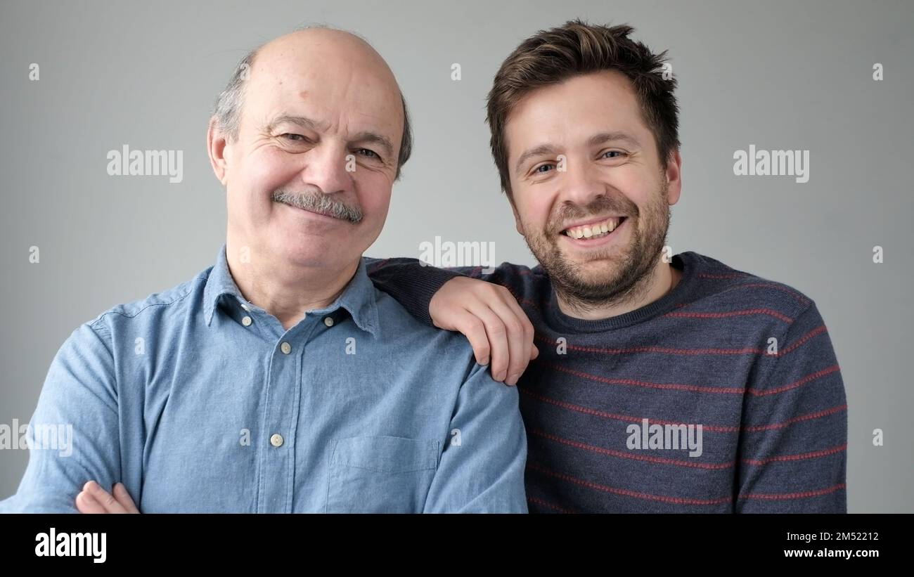 Happy mature senior father and grown son standing together, hugging ...