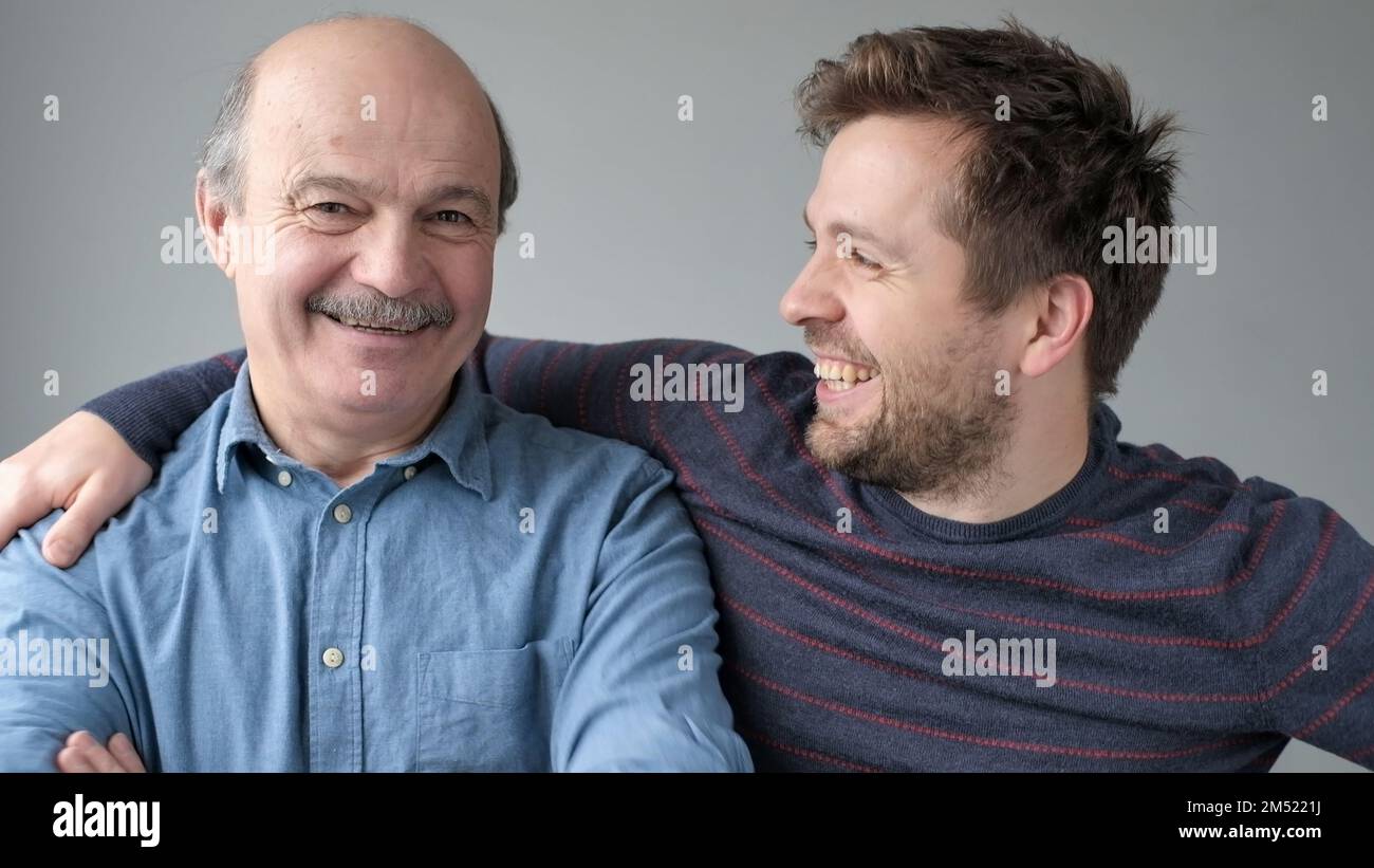 Happy mature senior father and grown son standing together, hugging ...