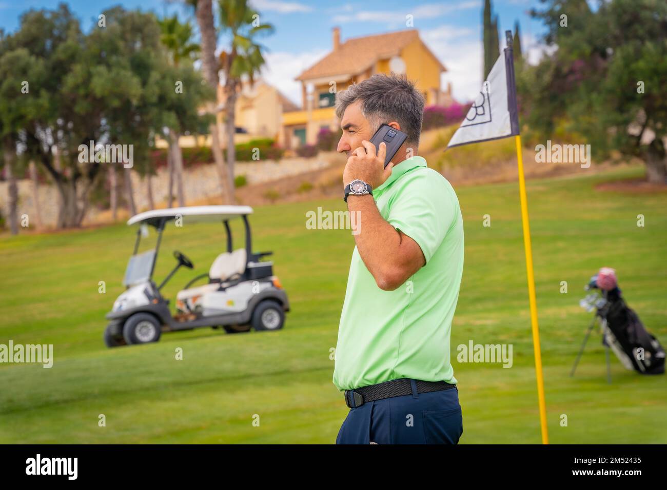 A professional male golf player on a phone while playing golf at golf ...