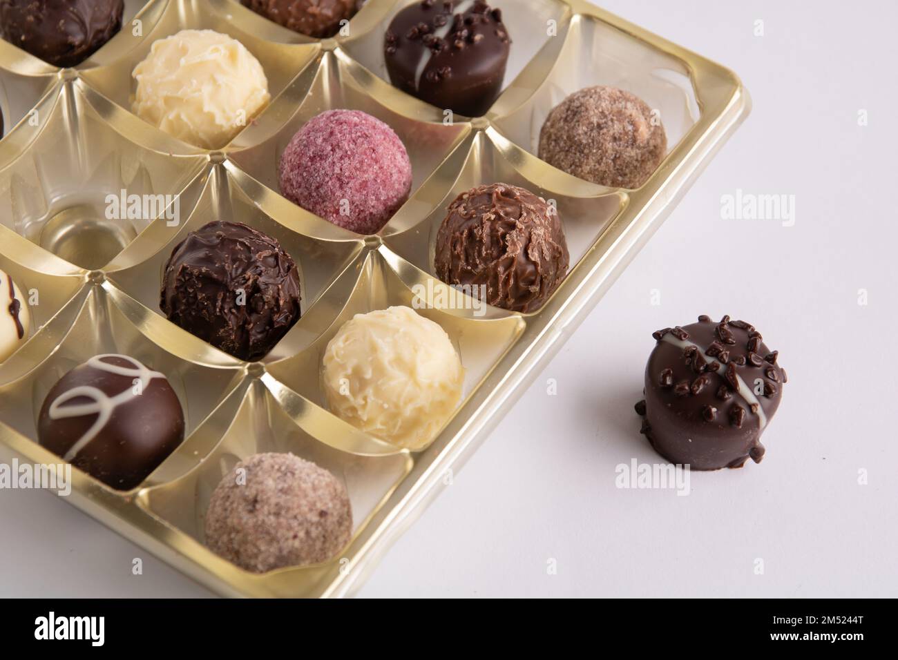 photo of round chocolates lying in a box on a white background Stock ...