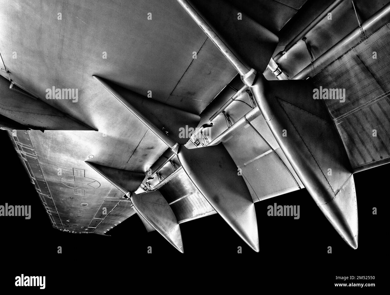 A military aircraft wing and flaps from the underside. Photo is black ...