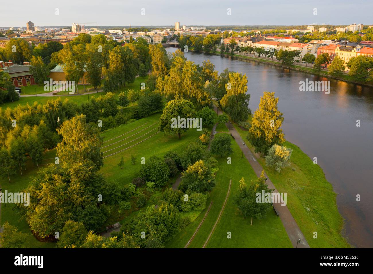 An aerial view of a town with a long river and green nature at sunset ...
