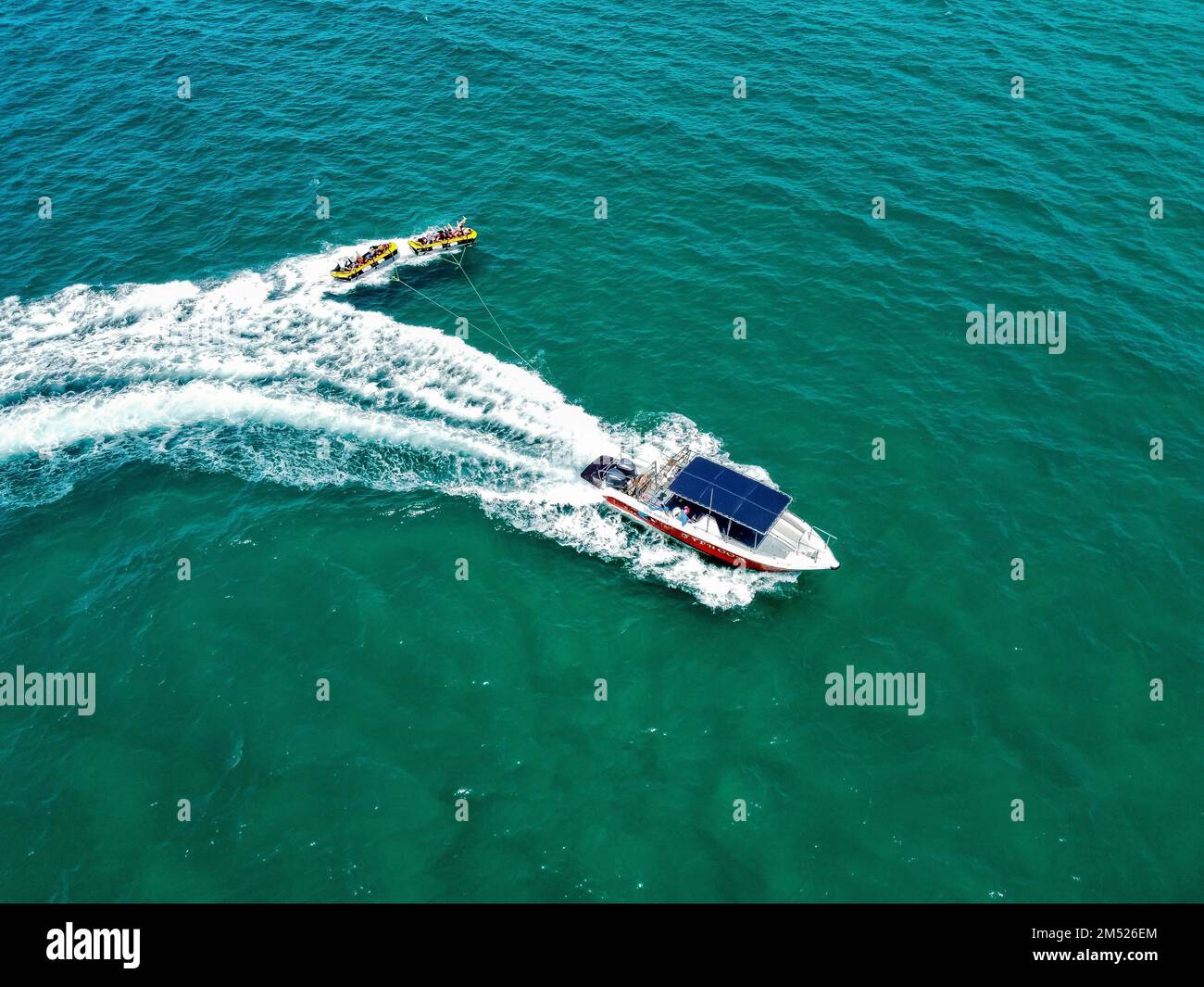 A top view of a boat with two athletic ride boats on a sea by the coast ...