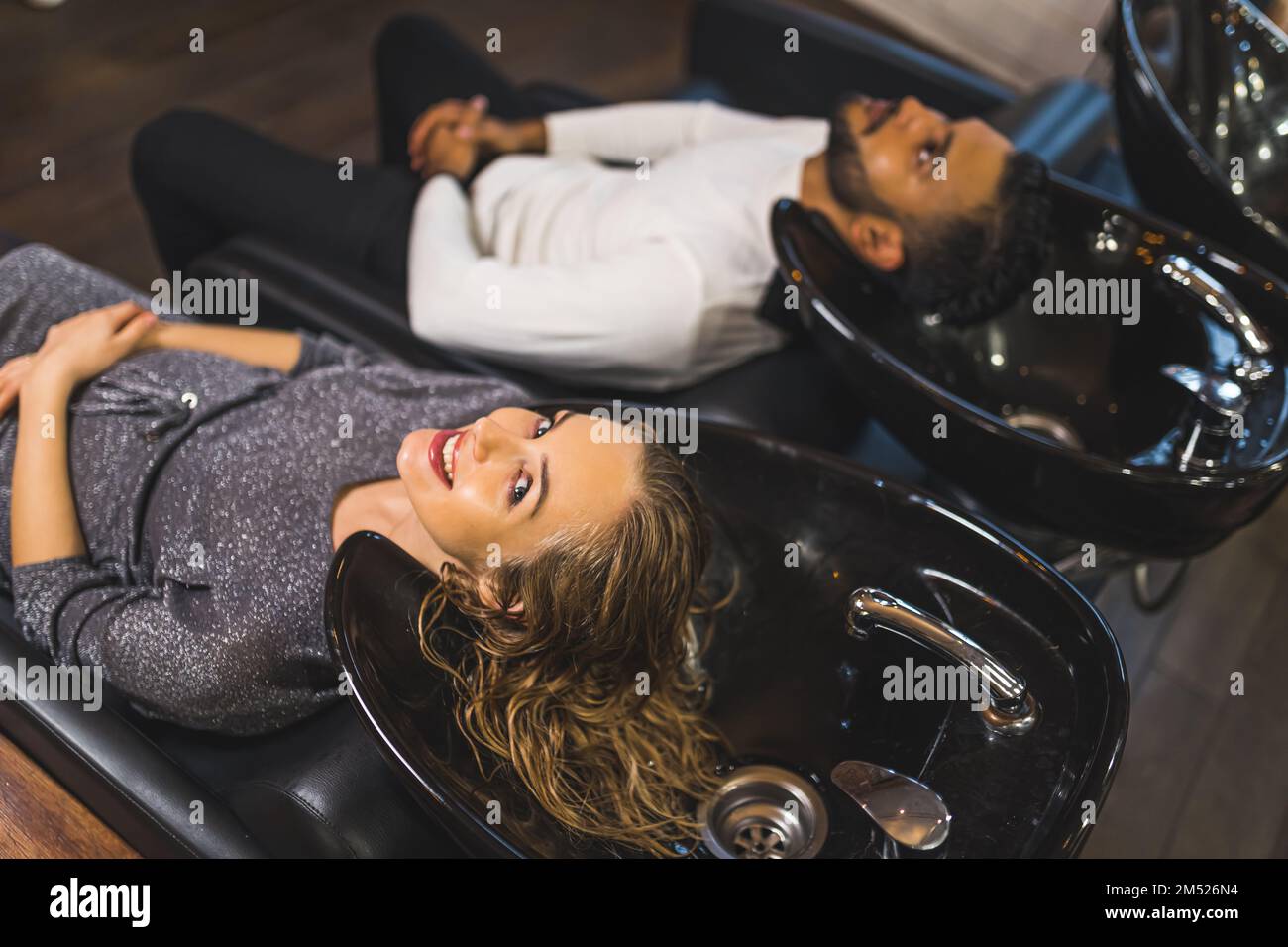 Happy male and female clients having their hair washed in the ...