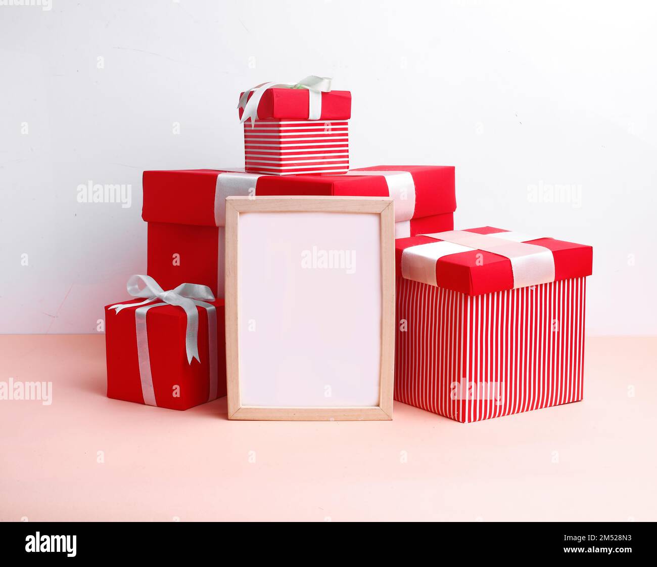 Cute Christmas setup with red gift boxes and blank wooden frame in the ...