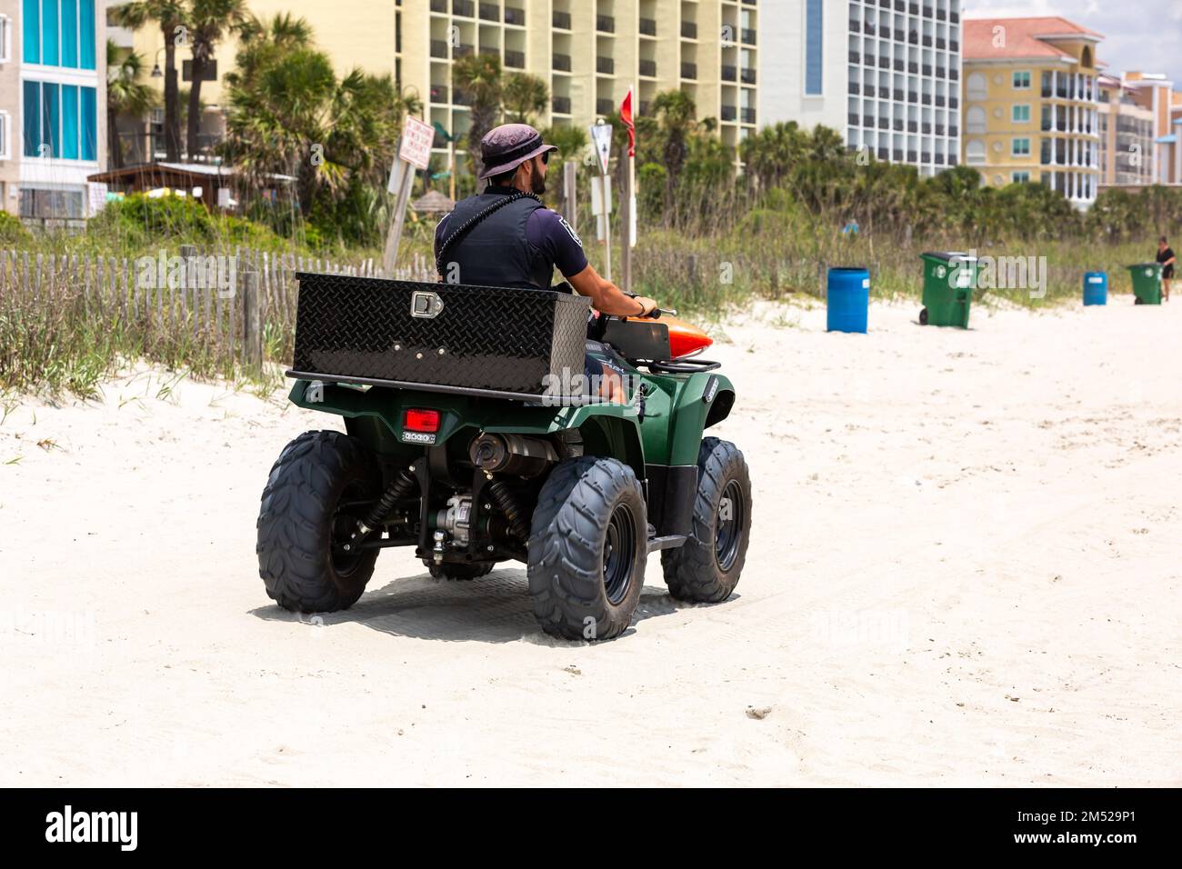 A police officer patrols the beach on a green Yamaha Kodiak ATV at ...
