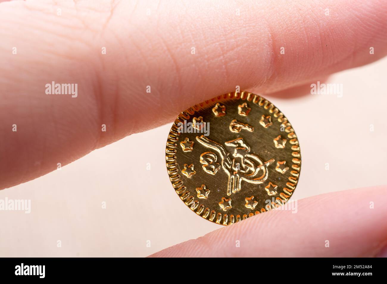 Fake gold coins in hand between fingers on canvas Stock Photo - Alamy