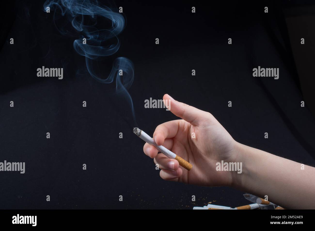 Hand is holding smoking cigarette with smoke around Stock Photo - Alamy