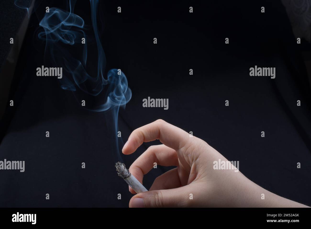 Hand is holding smoking cigarette with smoke around Stock Photo - Alamy
