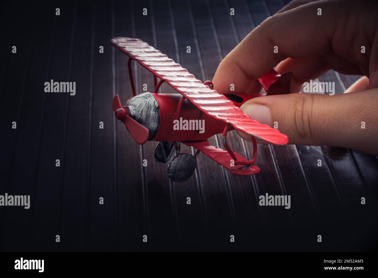 Hand holding a red toy plane on a on wooden texture Stock Photo - Alamy
