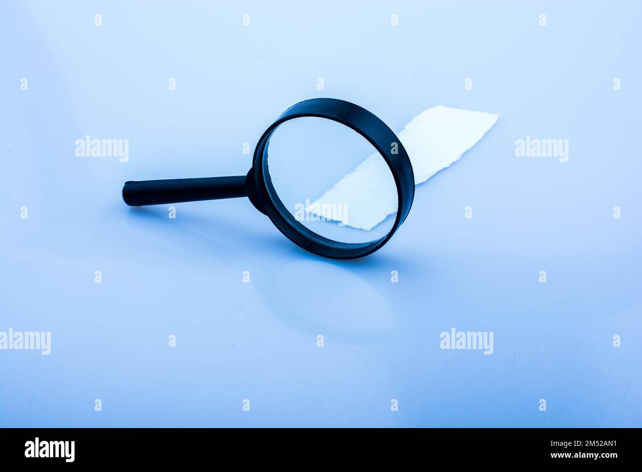 Piece of torn paper placed under magnifying glass Stock Photo - Alamy