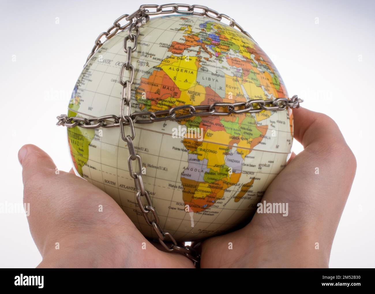 Hand holding a globe in chains Stock Photo - Alamy