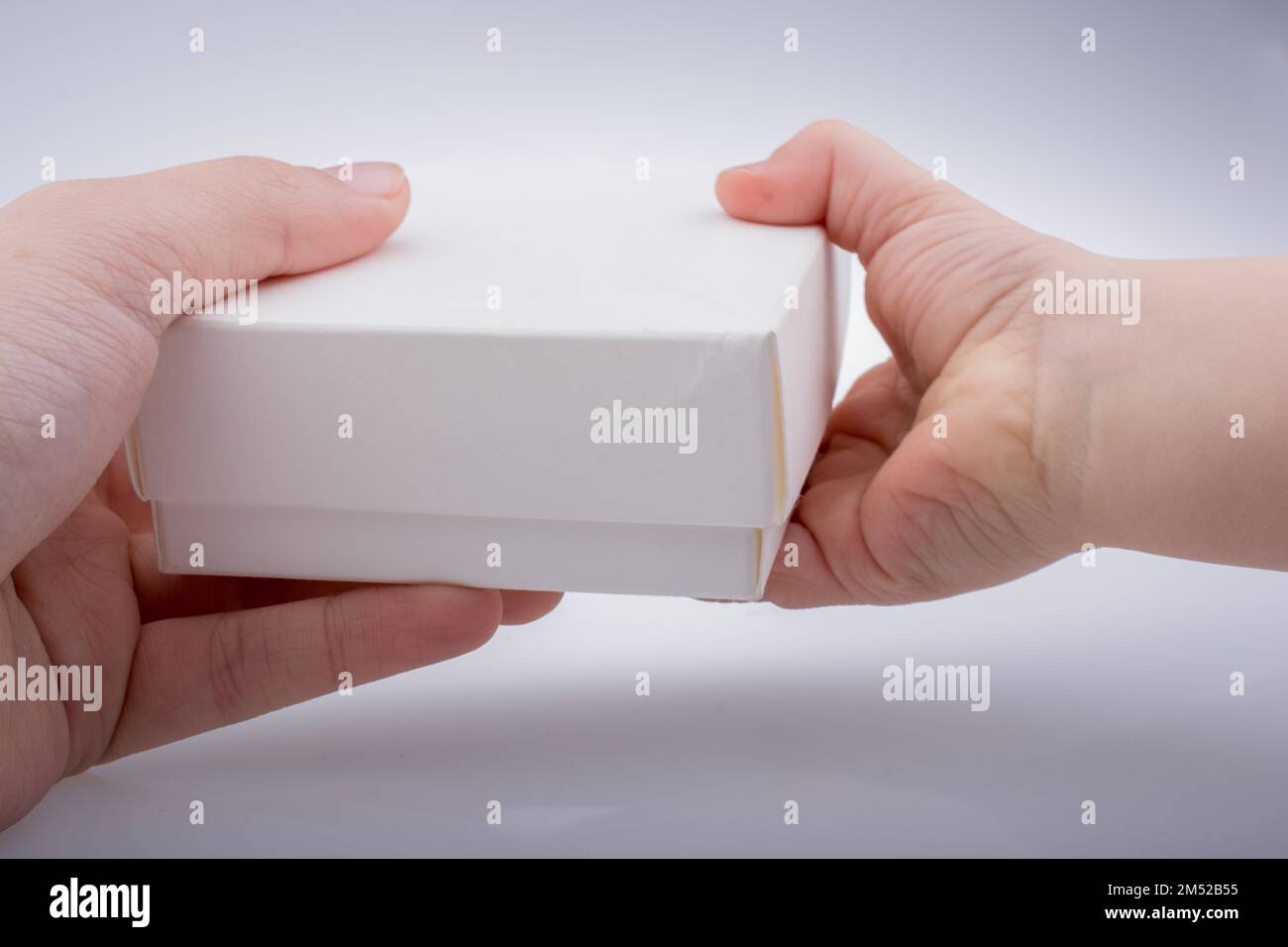 Hand giving a white gift box out Stock Photo - Alamy