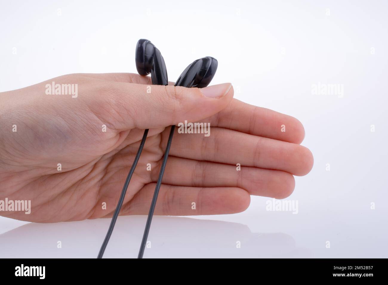 Hand holding a black earphone on a white background Stock Photo - Alamy