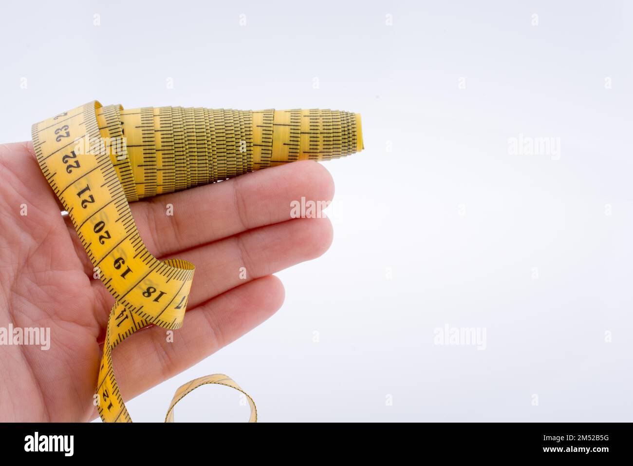 Hand holding a yellow color measuring tape on a white background Stock ...