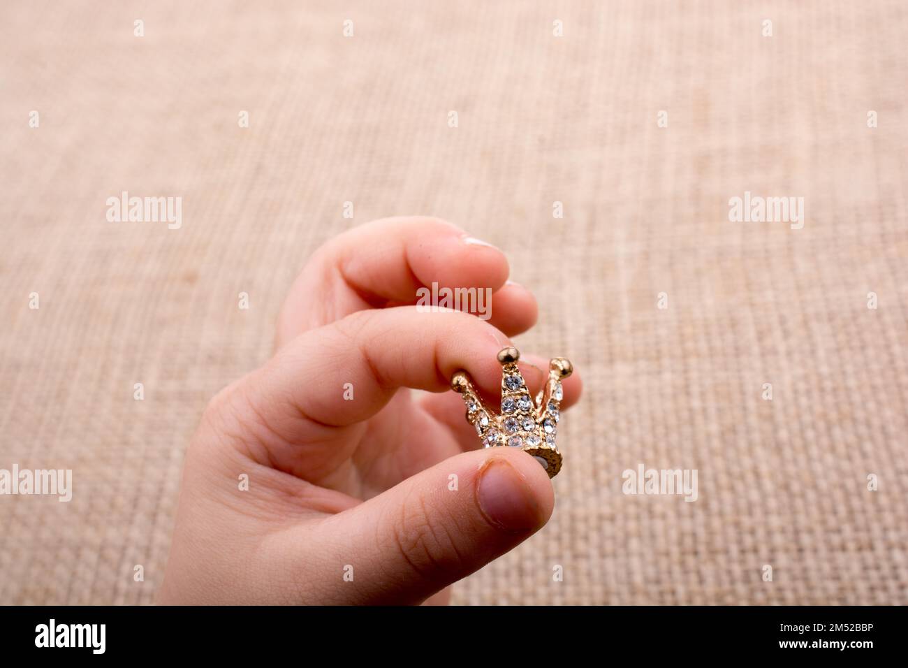Hand holding a little model crown in hand Stock Photo - Alamy