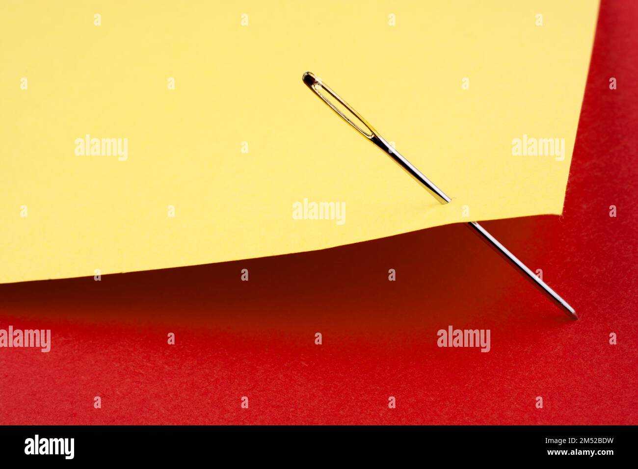 Needle pierced yellow color note paper on red one Stock Photo - Alamy