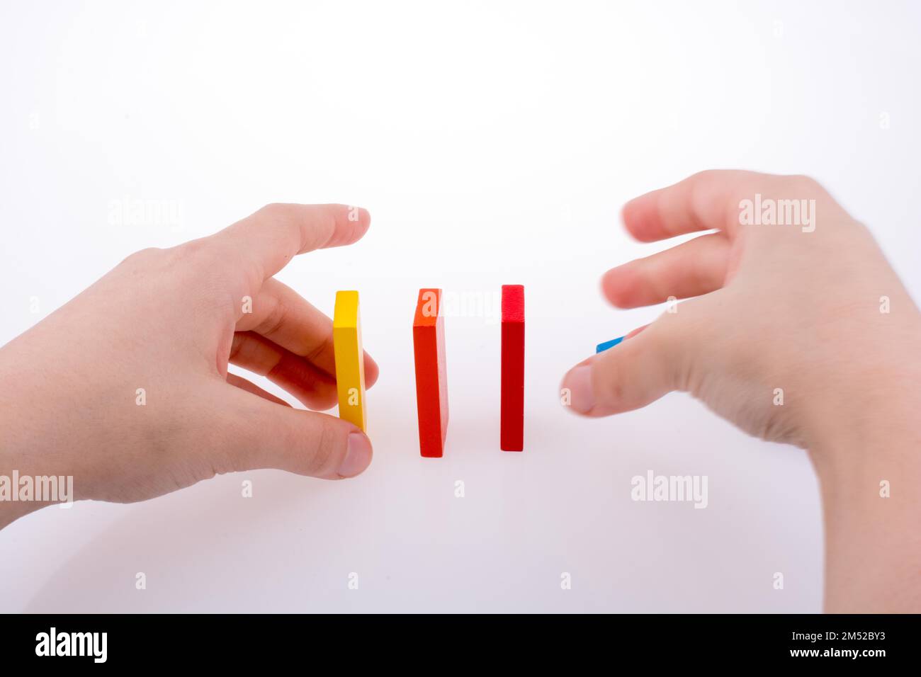 Hand playing with colored domino on white background Stock Photo - Alamy