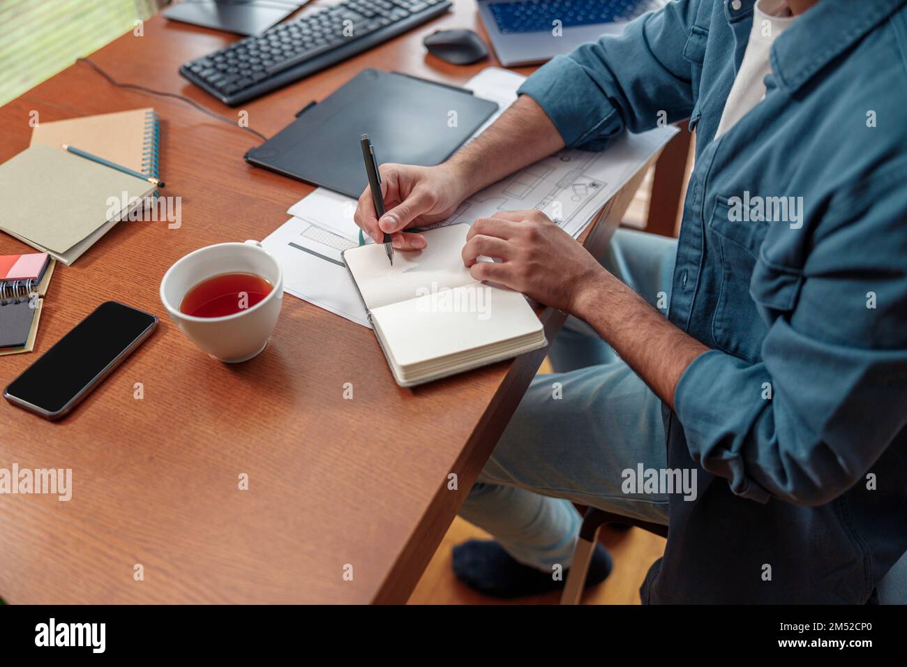 Close up of man hands making notes in notepad while sitting on his ...