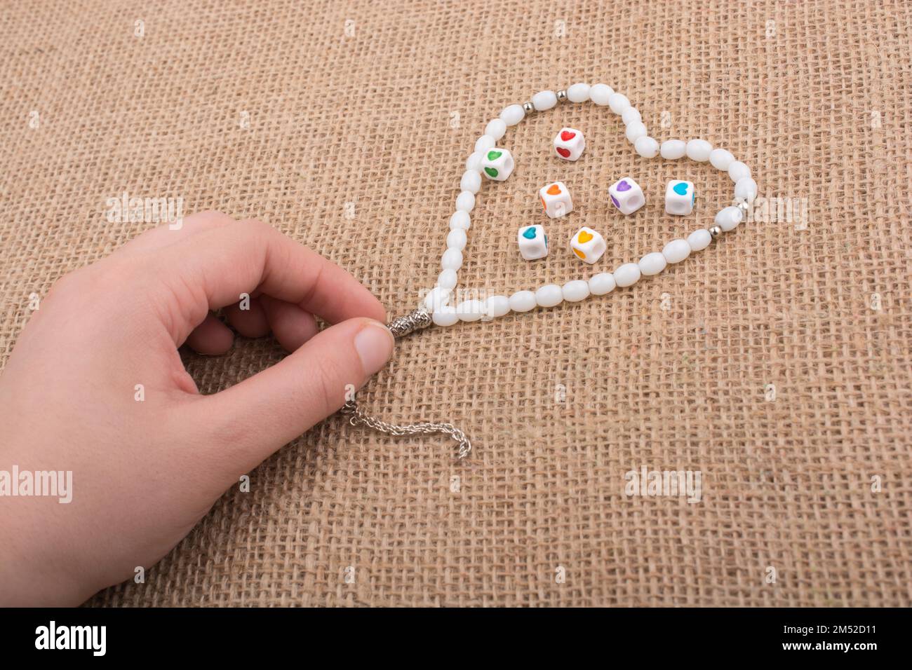Heart shaped object in hand by a praying beads on canvas Stock Photo ...