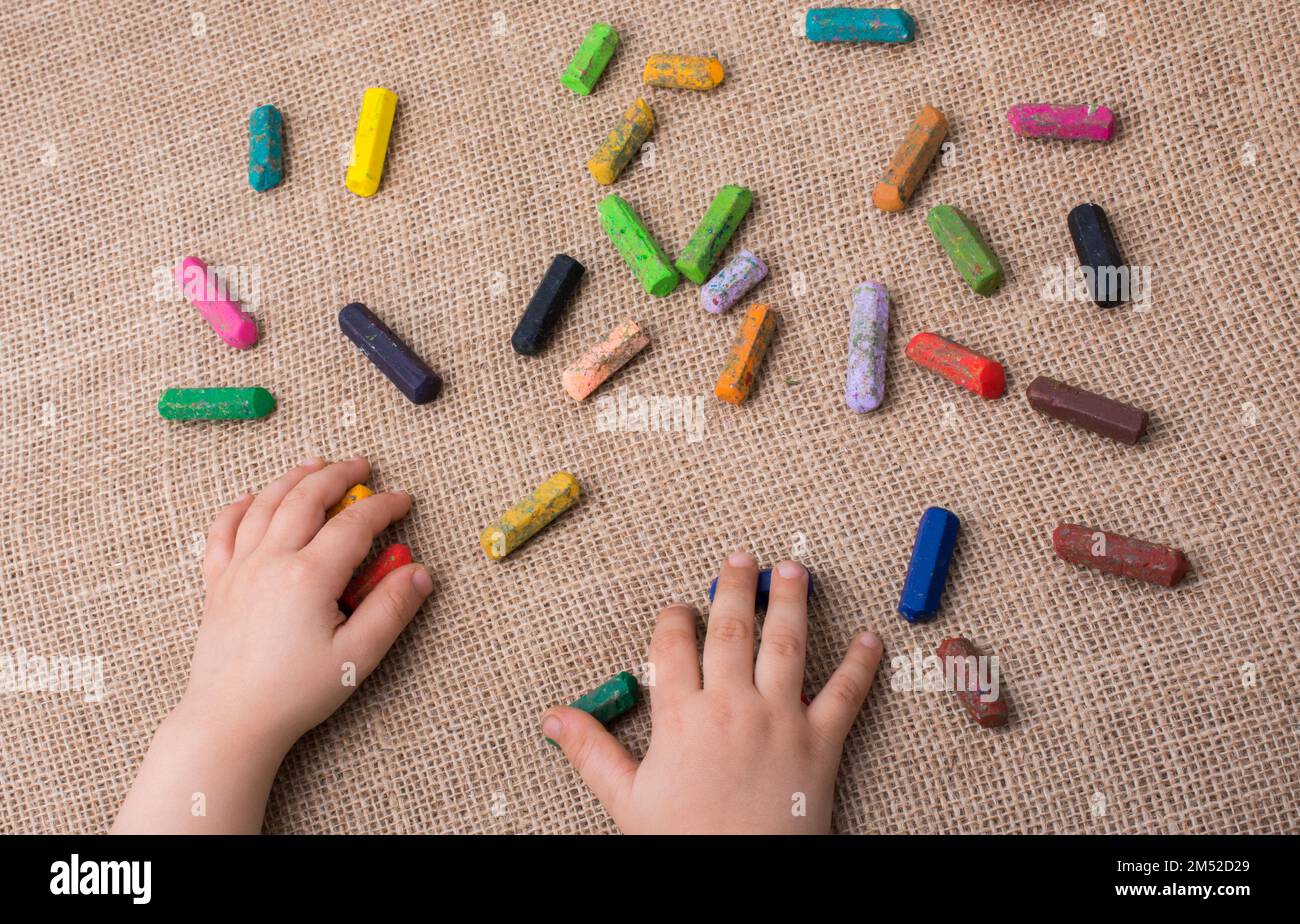 Used color crayons and a toddlers hand holding one Stock Photo - Alamy