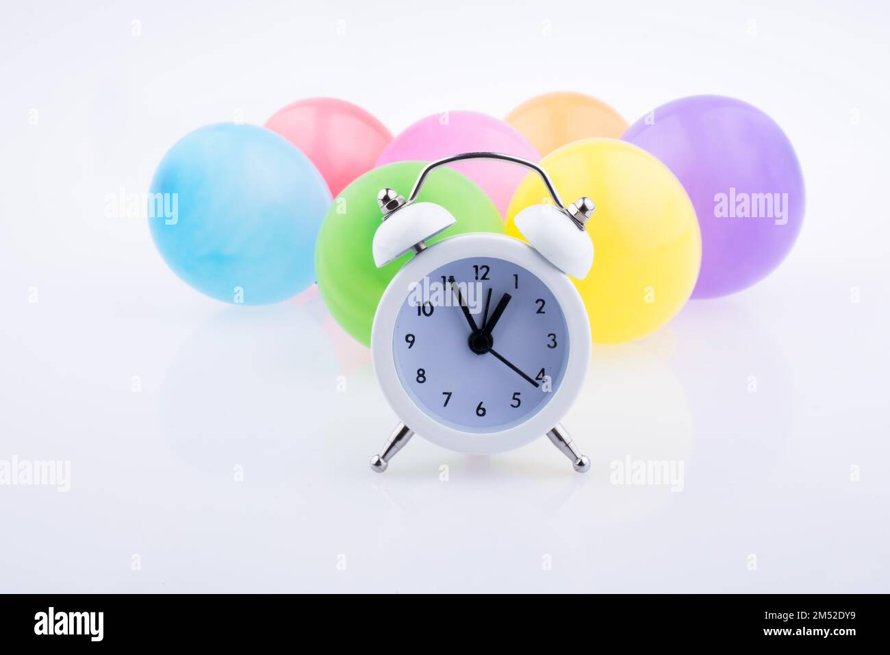 Alarm clock and colorful small balloons on a white background Stock ...