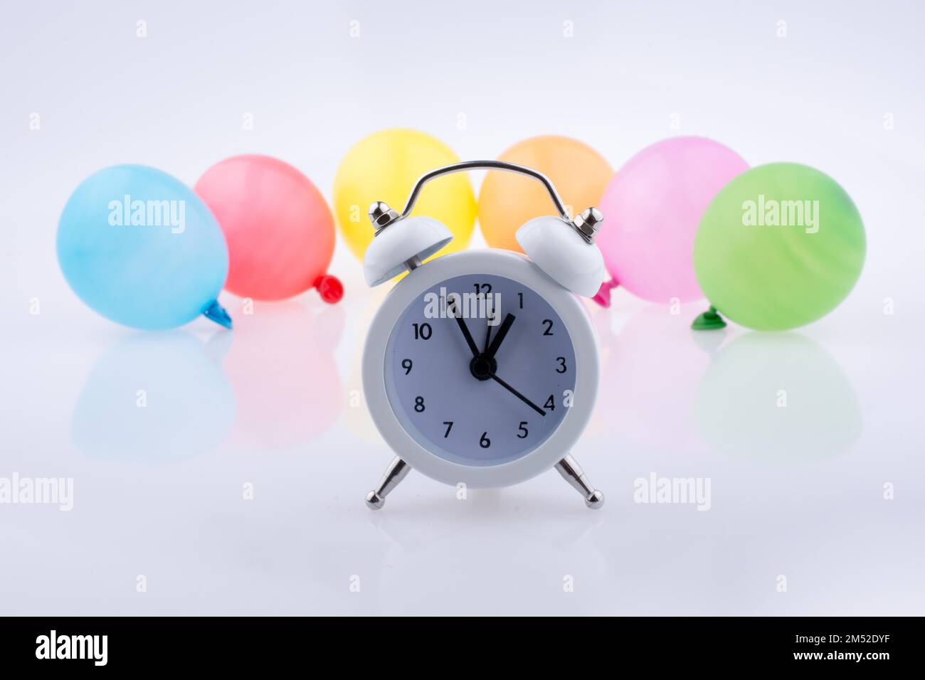 Alarm clock and colorful small balloons on a white background Stock ...