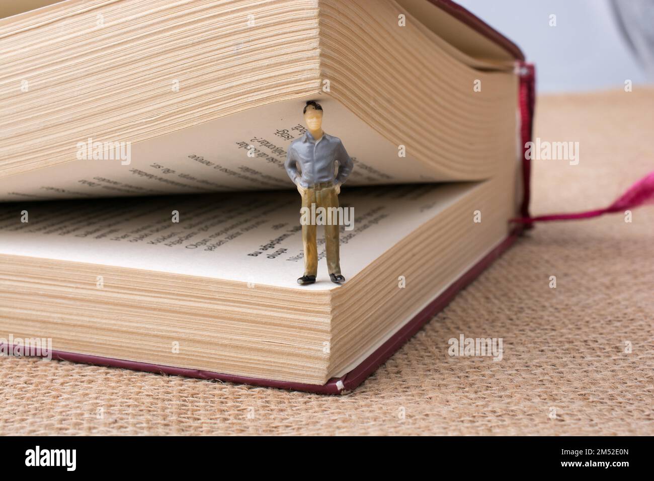 Man figurine standing inside the pages of the book Stock Photo - Alamy