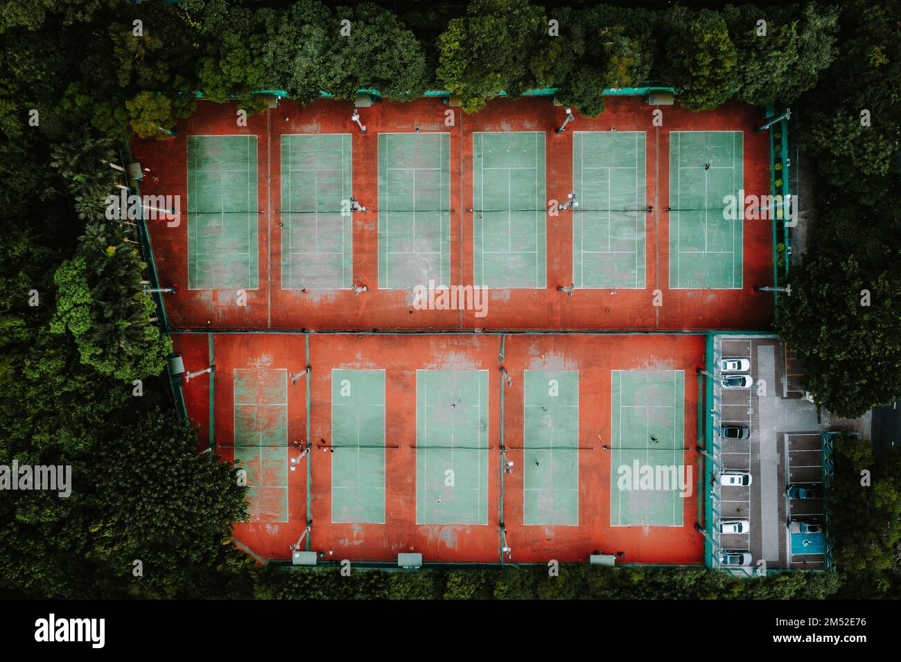 A top view of multiple red and green tennis courts set inside a jungle ...