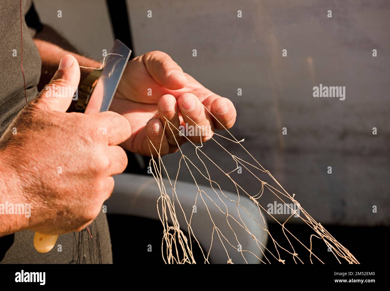 hands of fisherman with nets and knife for repair Stock Photo - Alamy