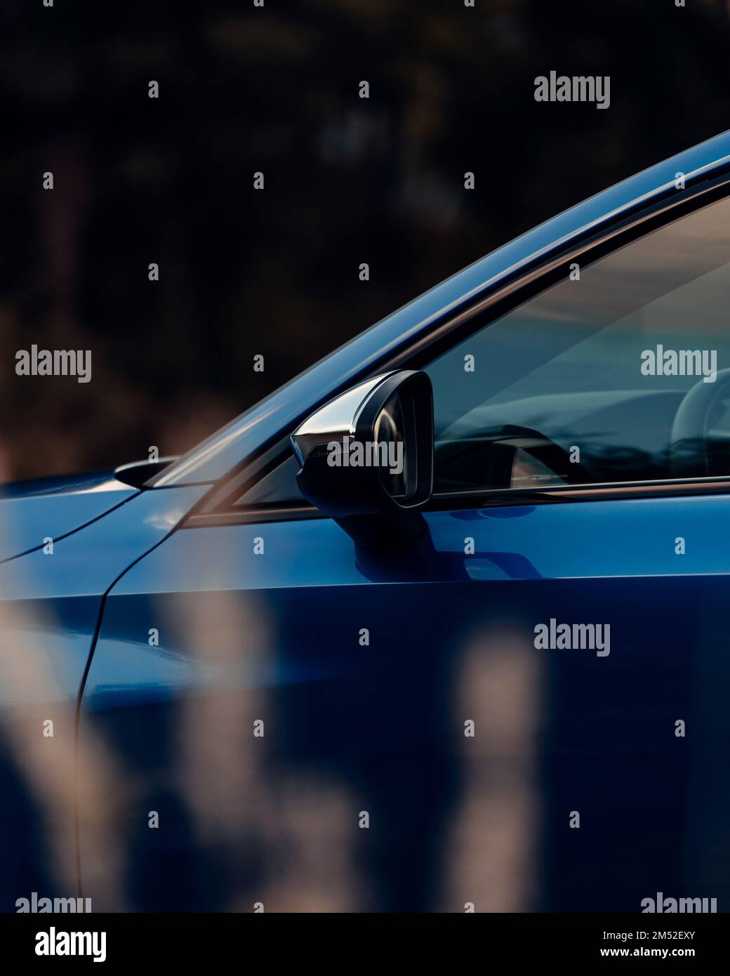A side shot of a shiny blue sport car mirror with blur background ...