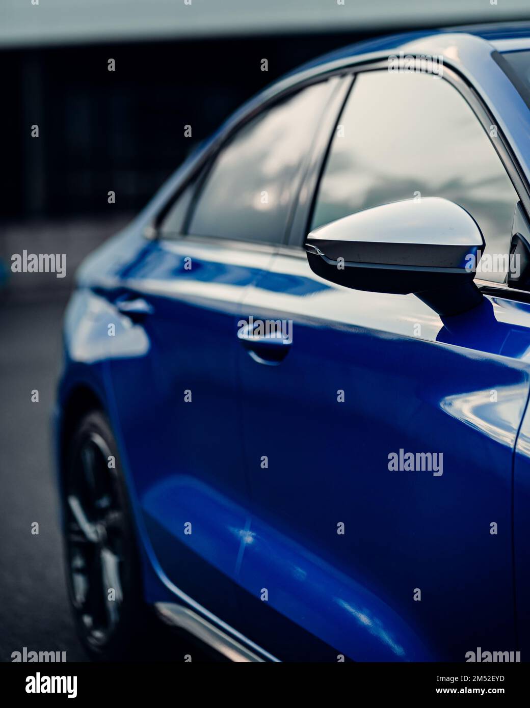 A side shot of a shiny blue sport car mirror and windows with blur ...