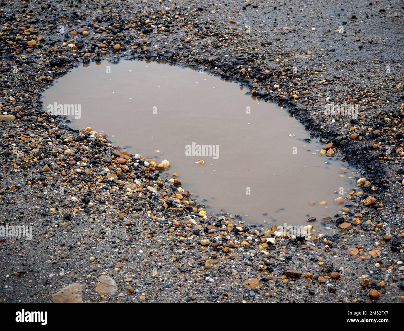 Pothole on a paved road on a rainy winter day. Concept of risk and ...