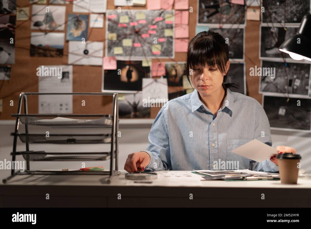 Detective working in her office at a desk with a magnifying glass and a ...