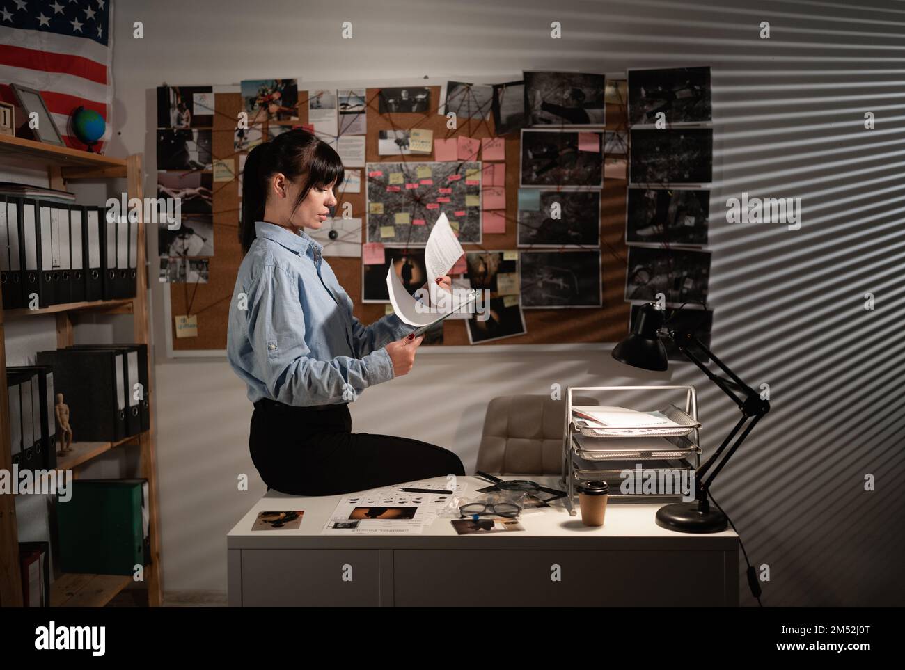 Young female detective looking through criminal profiles and picking up ...