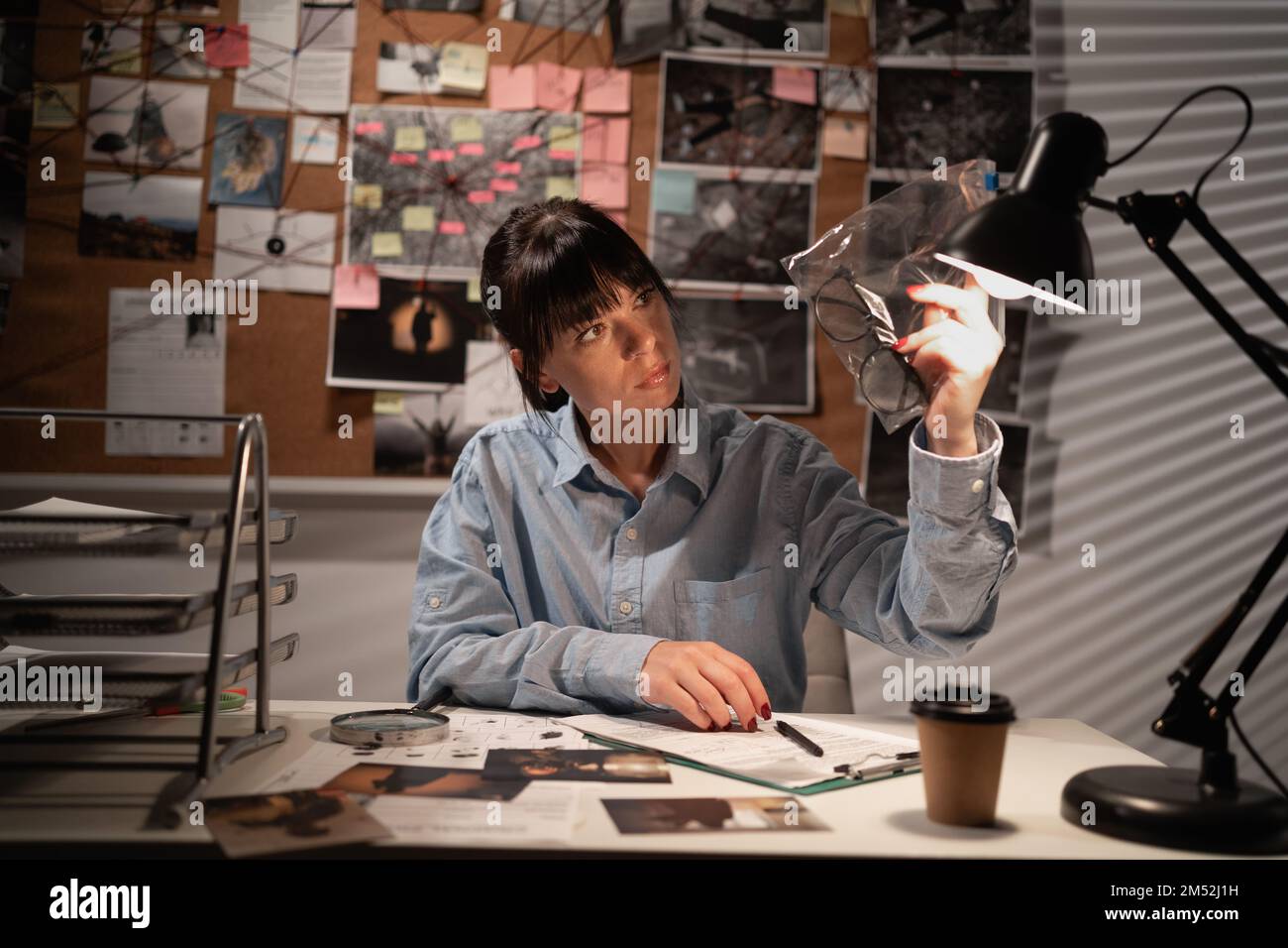 Detective working in her office with evidence. Coy space Stock Photo ...
