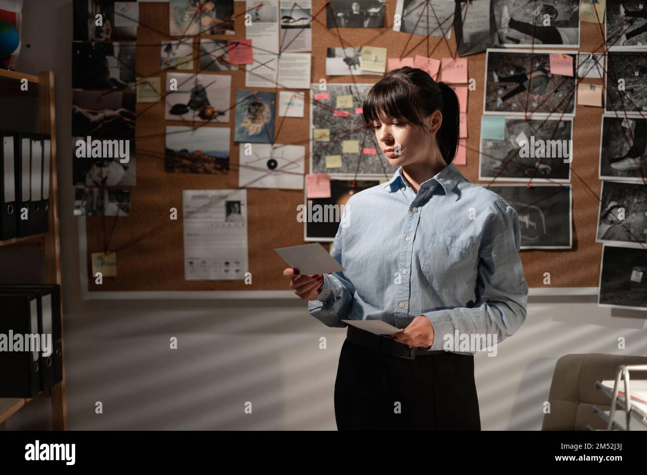 Detective working at desk in her office examining killer photos. Copy ...