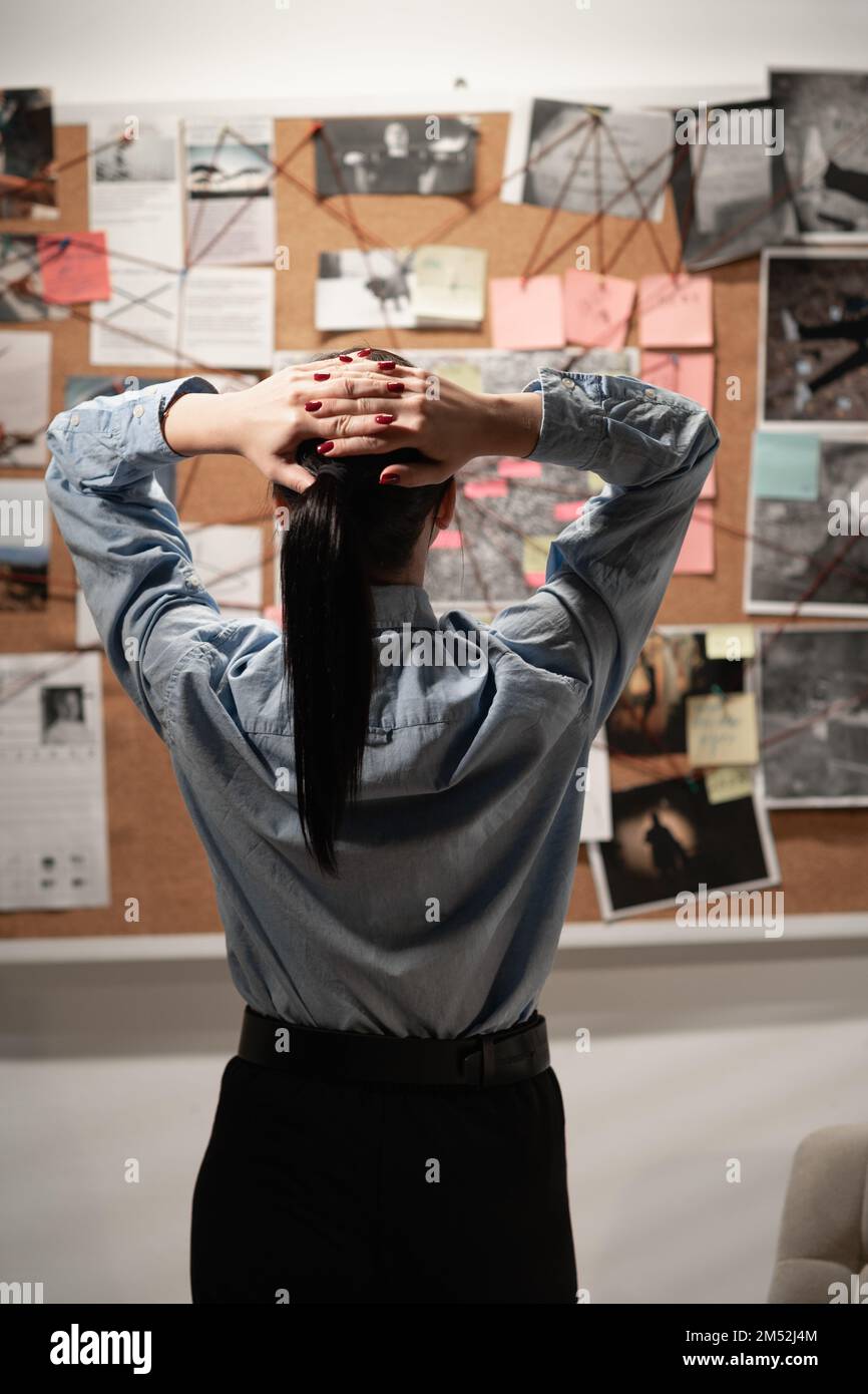 Lady private agent or detective looking at crime investigation board ...