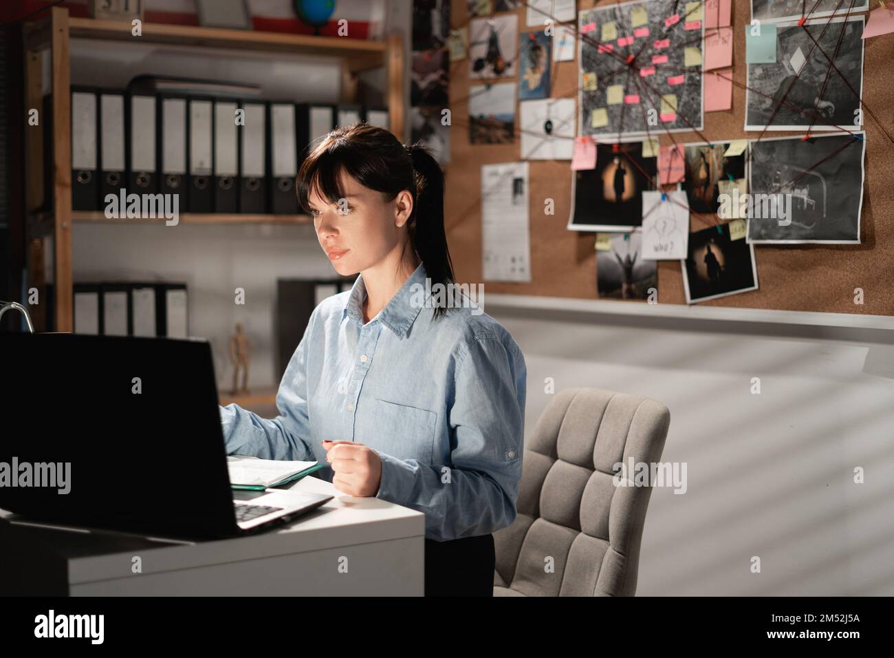 Young detective working in her office using laptop and internet, murder ...