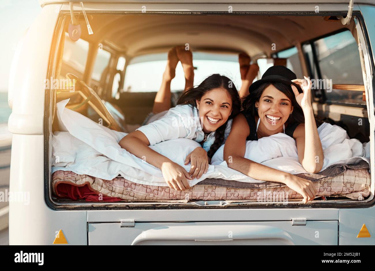 Chilling out, road trip style. two happy friends relaxing on a blanket ...
