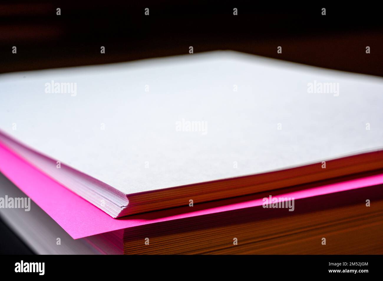 Selective focus on a single colored sheet in a stack of plain white ...