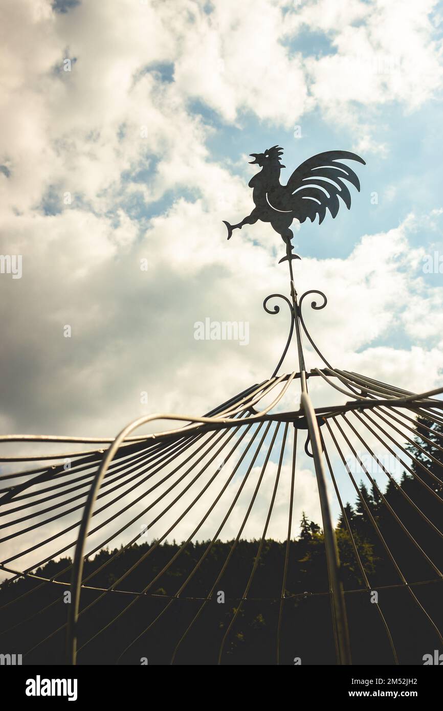 A low angle of a metal rooster on top of a metallic structure against ...