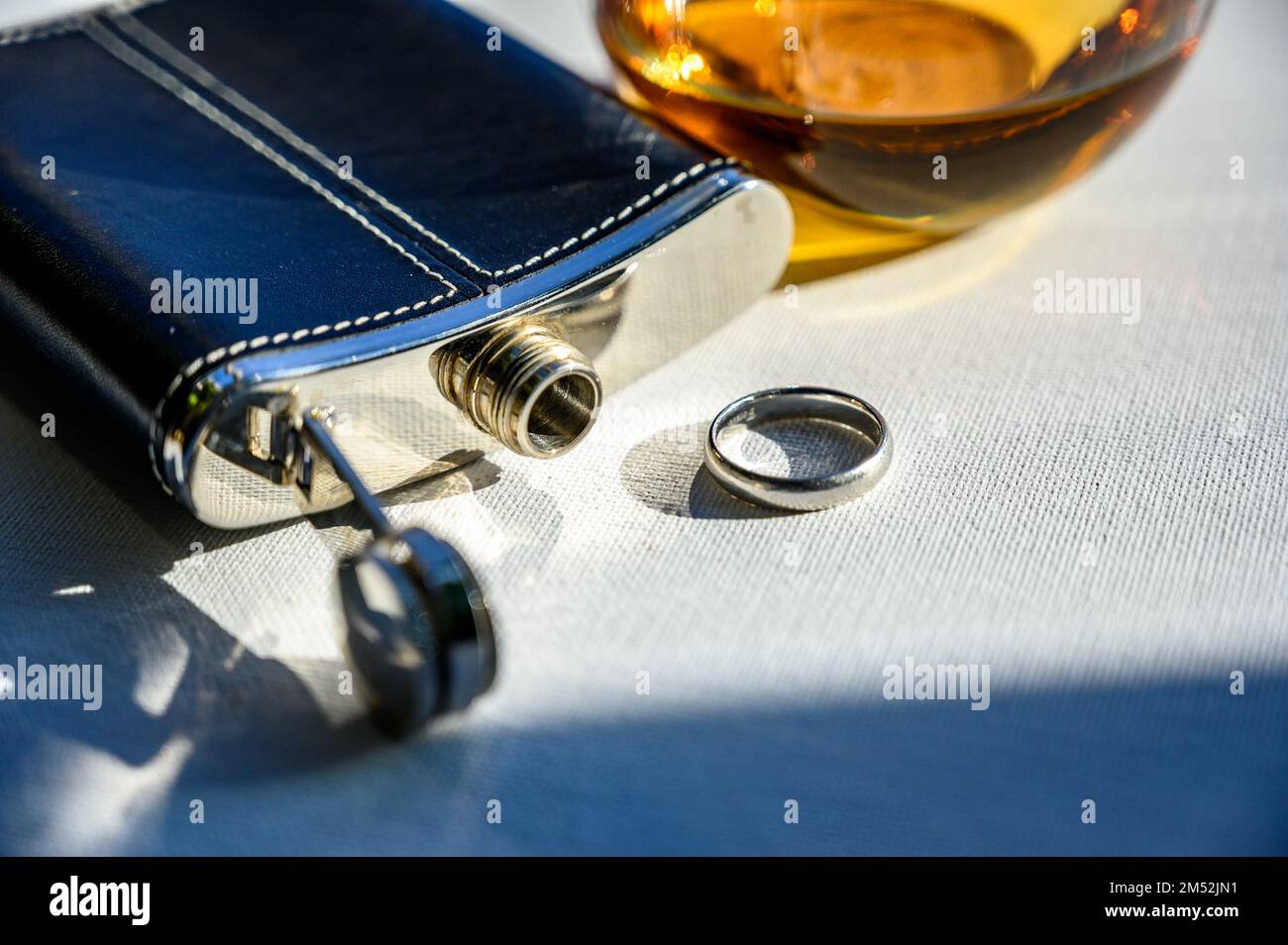 Black and silver whiskey flask next to a glass of amber colored liquid ...