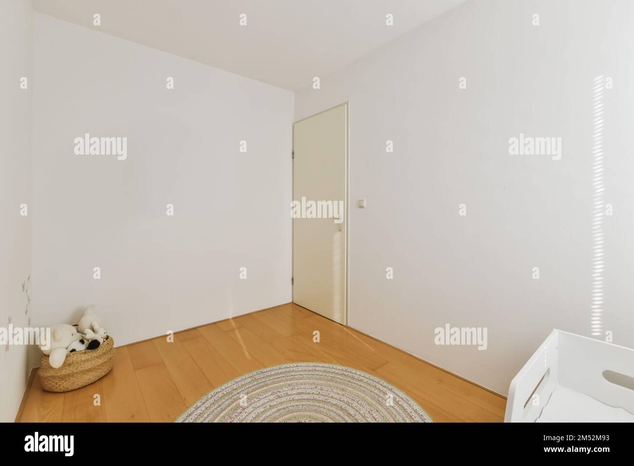 an empty room with white walls and wood flooring, there is a round rug ...