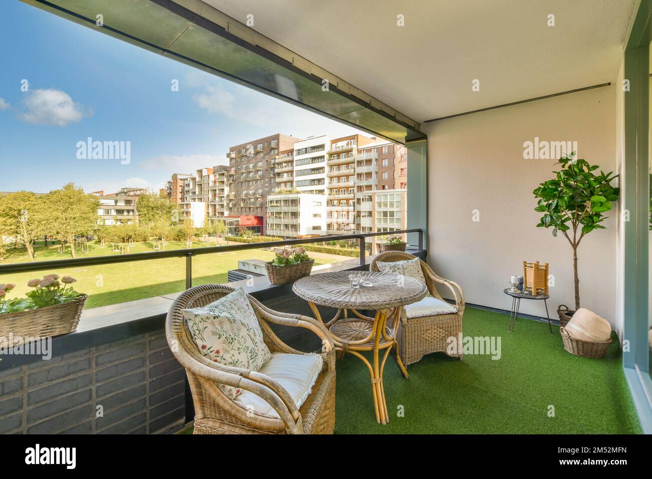 a balcony with chairs, tables and a plant on the grass area in front of ...