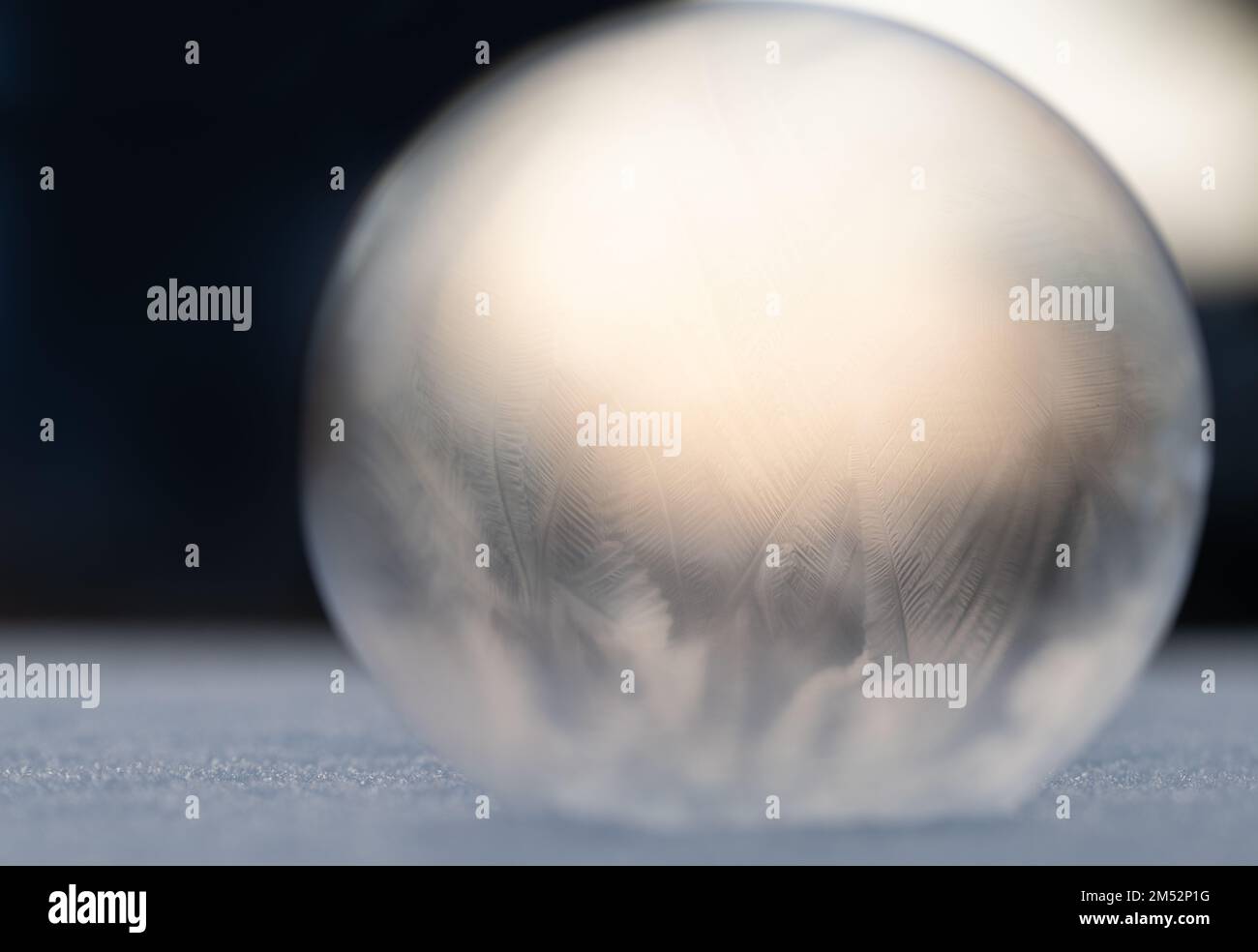 Close-up of a frozen soap bubble. The ball lies on snow. The background ...