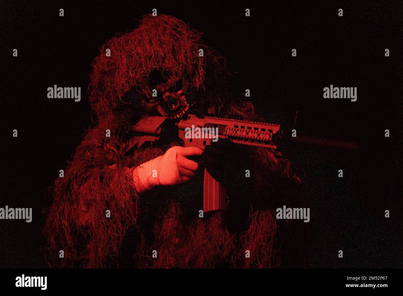 A dark horror shot of a male with a scary costume and skull mask with a ...